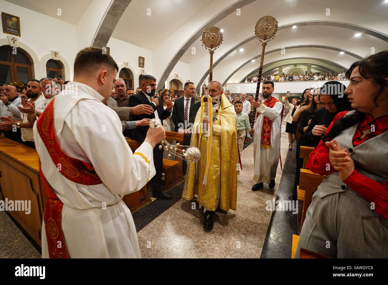 Al Hamdaniya, Iraq. 19th Apr, 2025. A Syriac Catholic priest carries ...