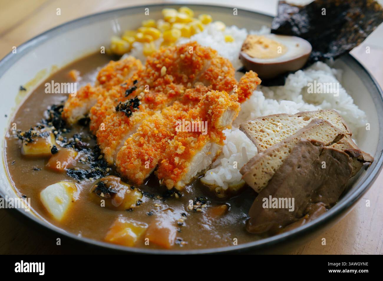 A plate of Japanese chicken katsu curry served with rice, egg, and ...