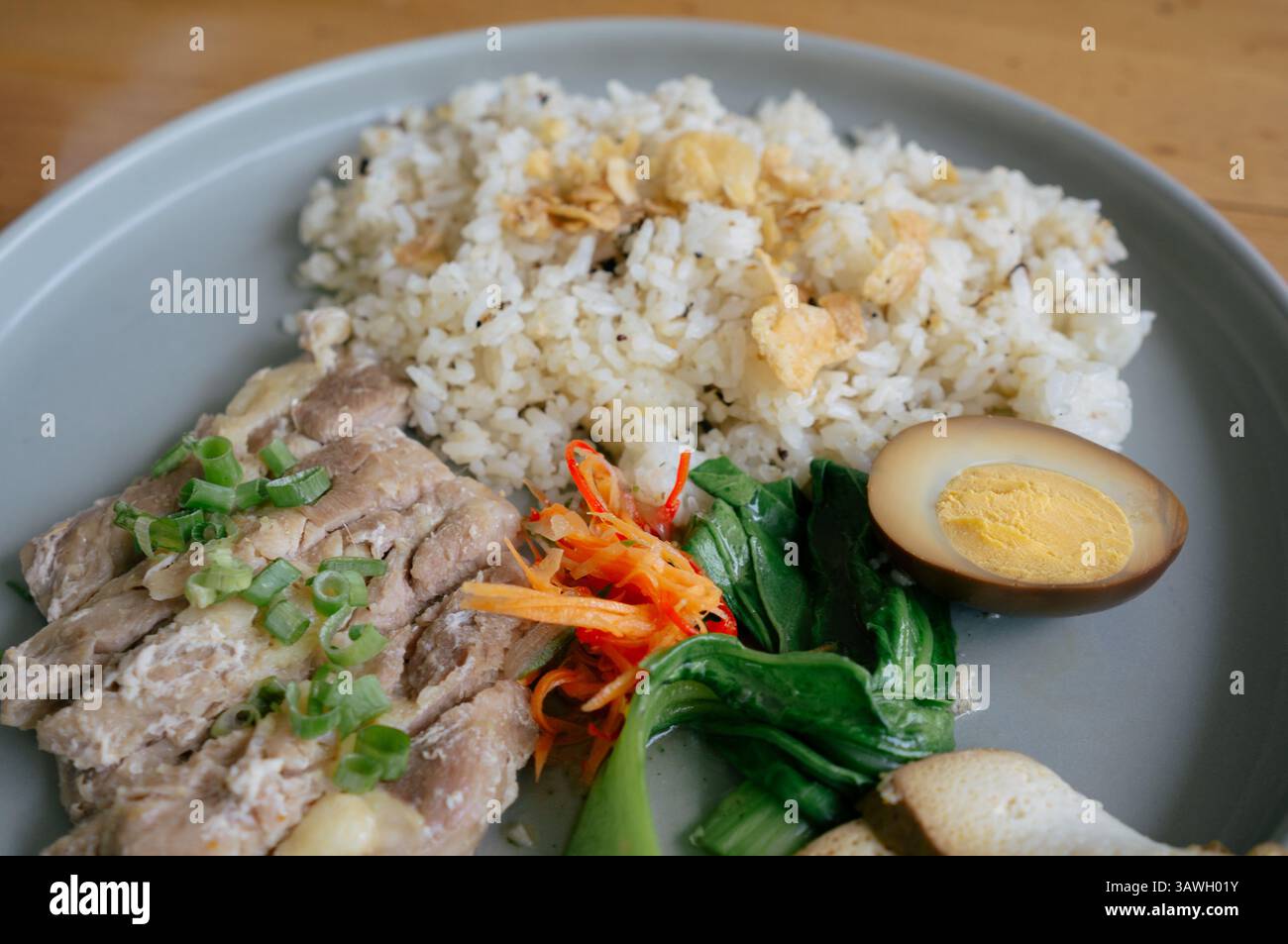 A plate of hainan chicken rice served with bok choy, egg and other ...