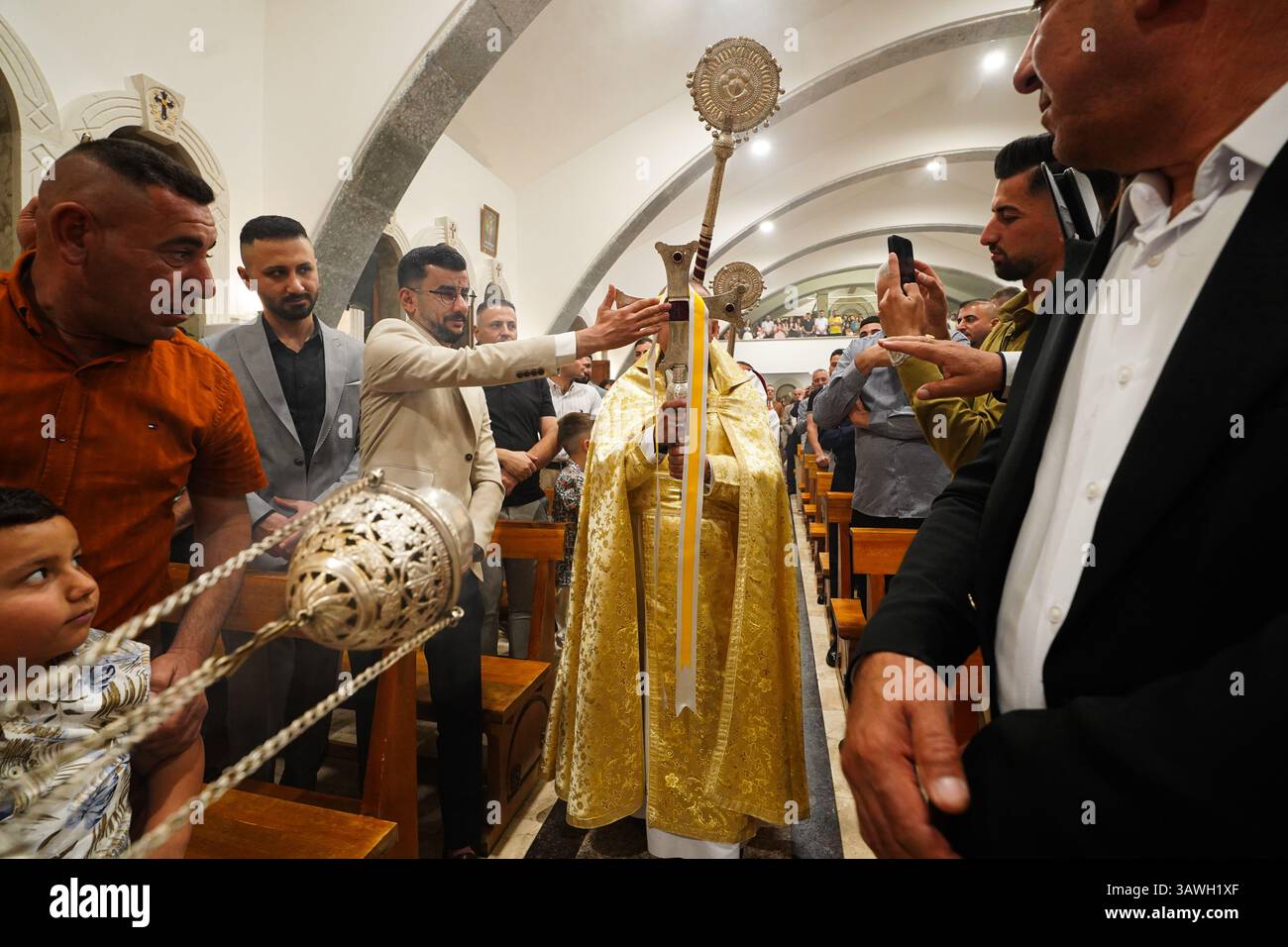 Al Hamdaniya, Iraq. 19th Apr, 2025. A Syriac Catholic priest carries ...