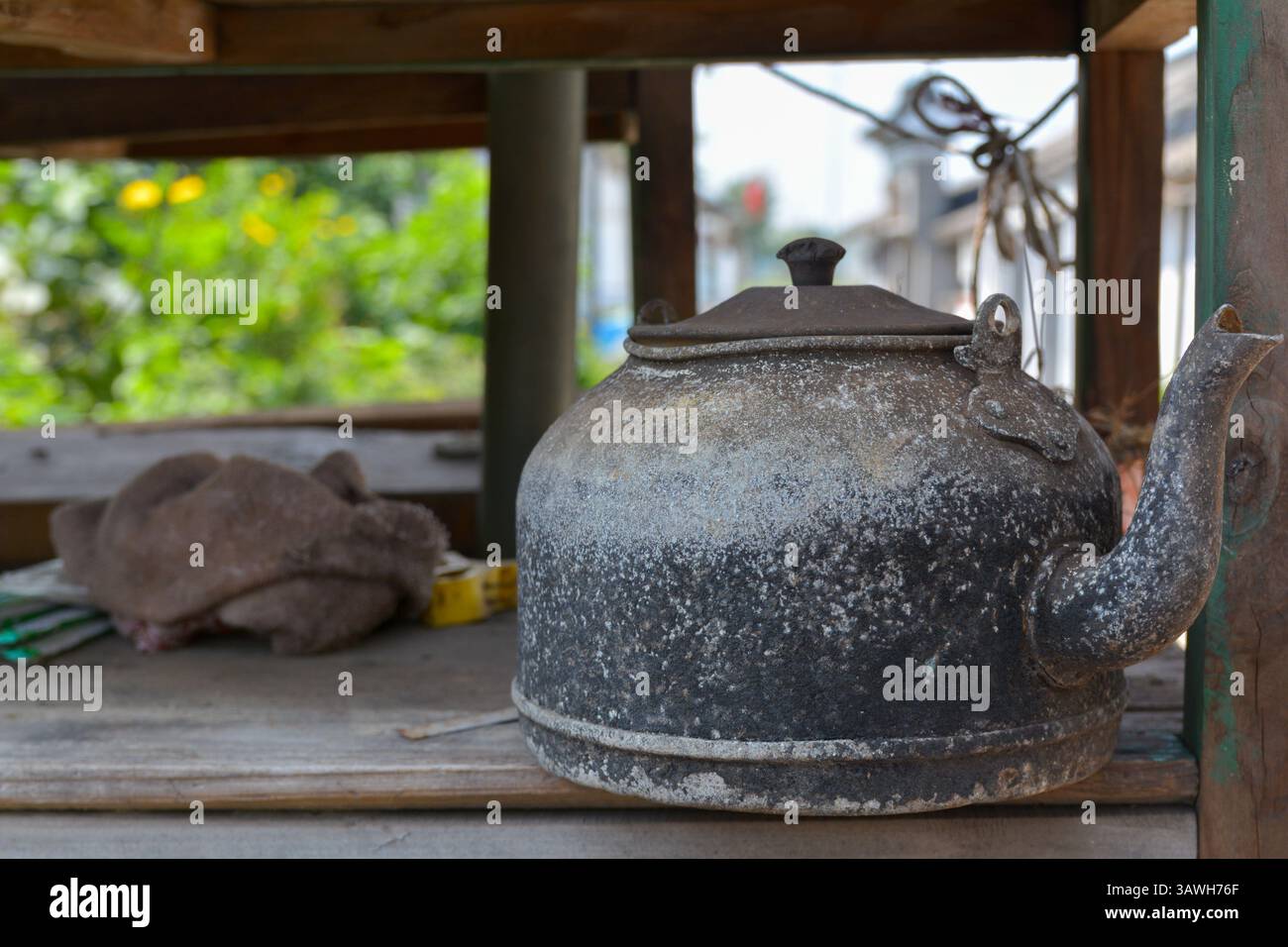 Old metal kettle on a shelf showing years of damage and use with an out ...