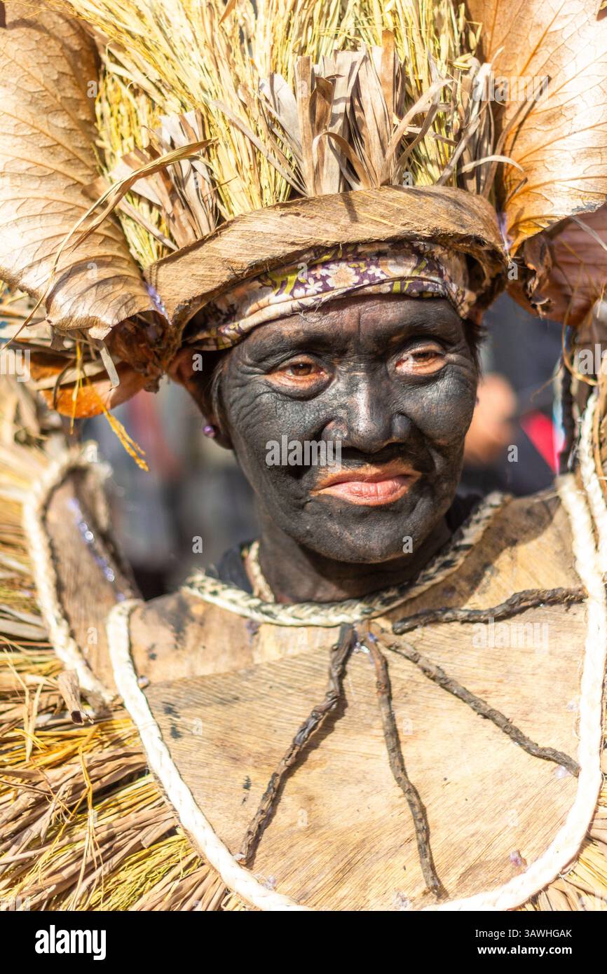 Participant in black face paint to honor the Ati tribe and wearing ...