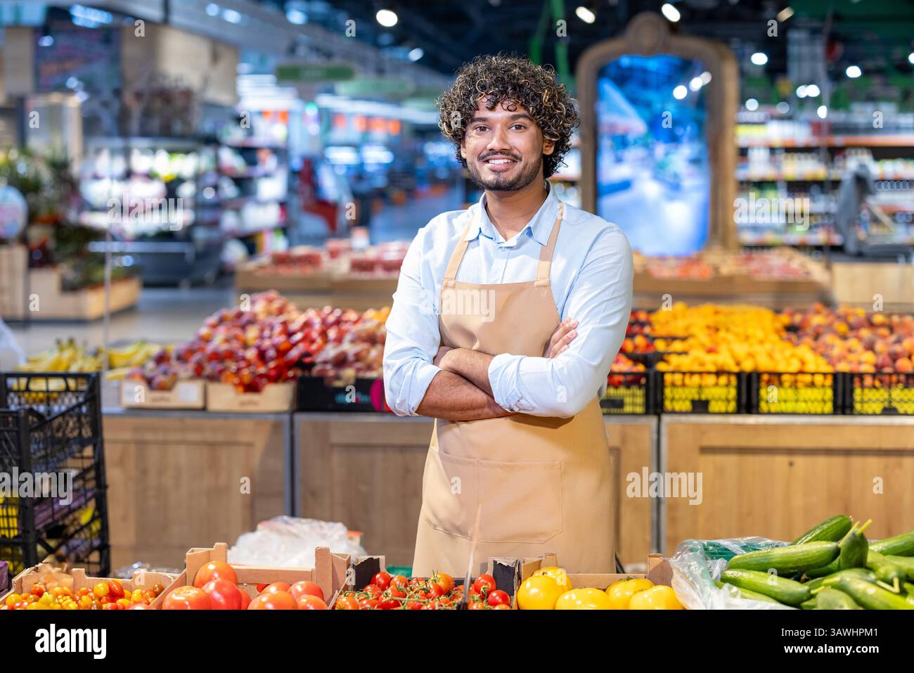 A friendly supermarket worker smiles proudly while standing in front of ...
