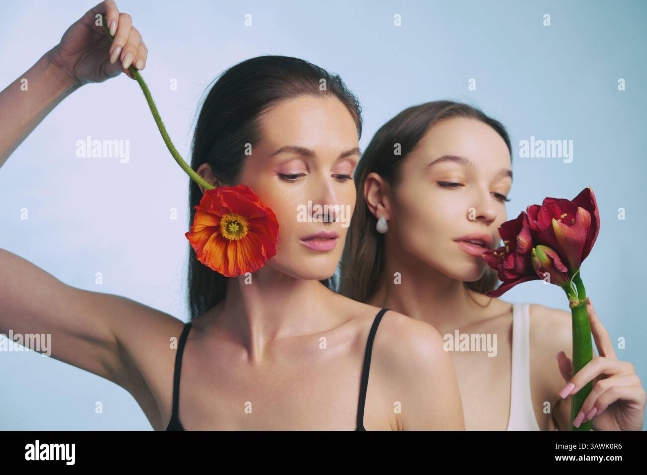 Two models interacting with vibrant flowers in a studio setting during ...