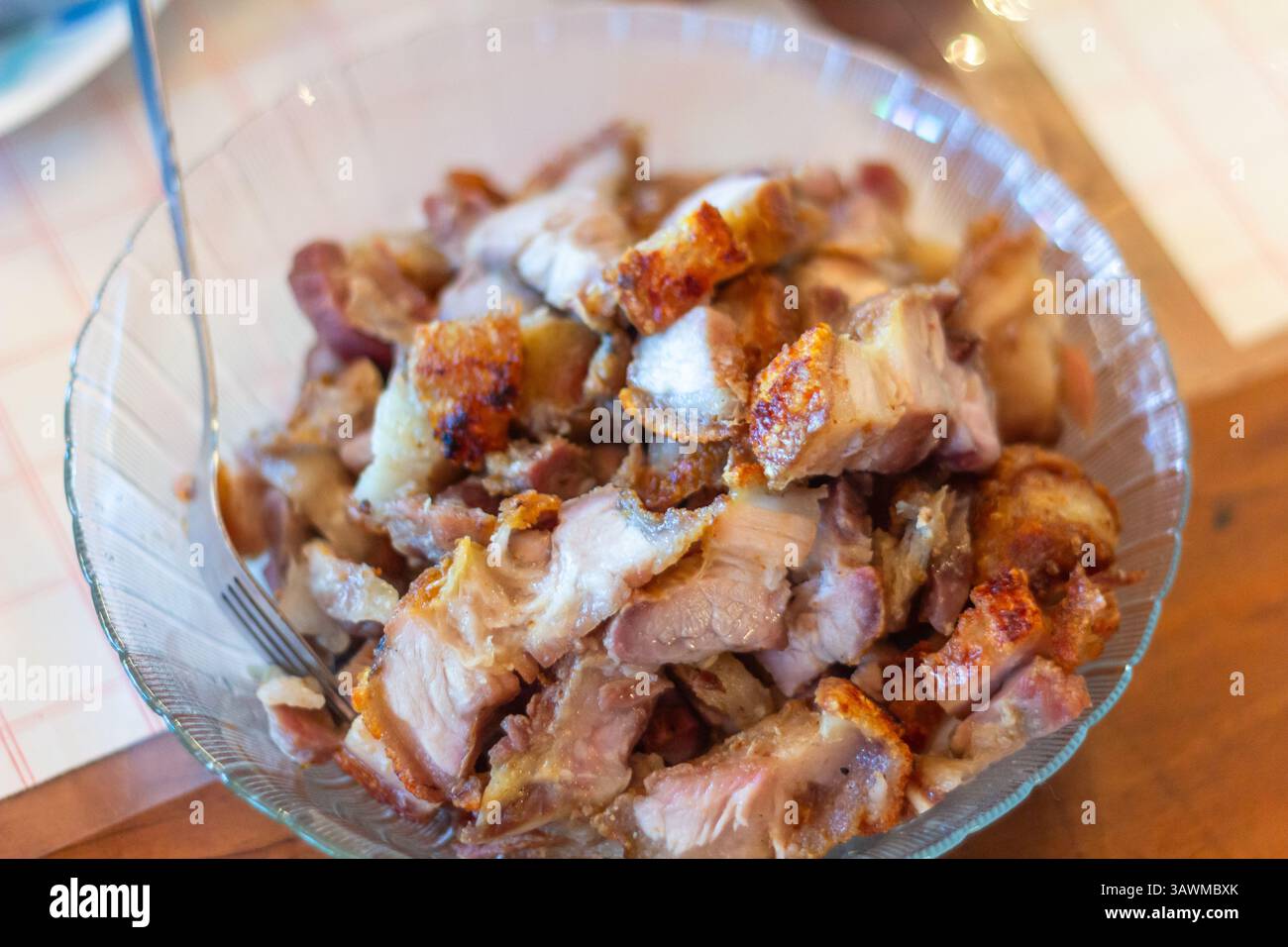 A glass bowl filled with chopped lechon kawali, a popular Filipino dish ...