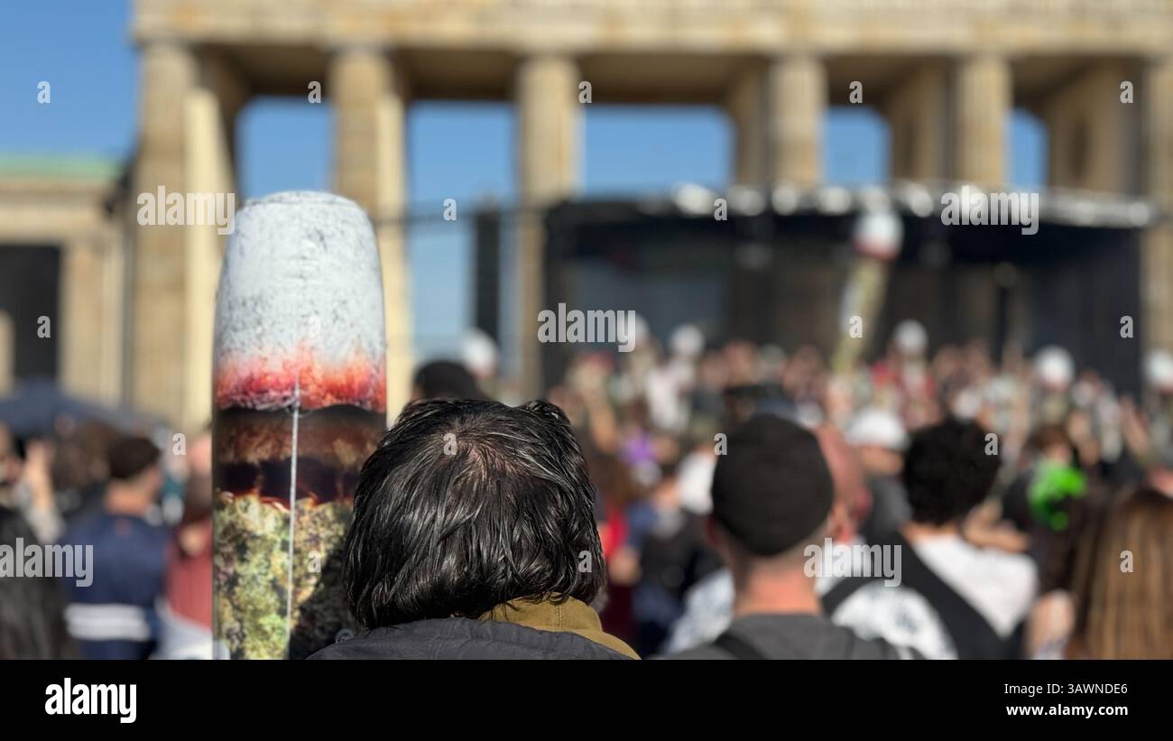 20 April 2025, Berlin: Numerous people stand with joints and giant inflatable joints at the ...