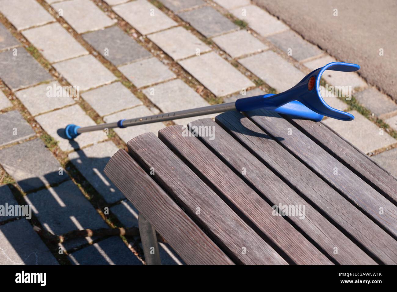 A blue cane is leaning against a wooden bench Stock Photo - Alamy