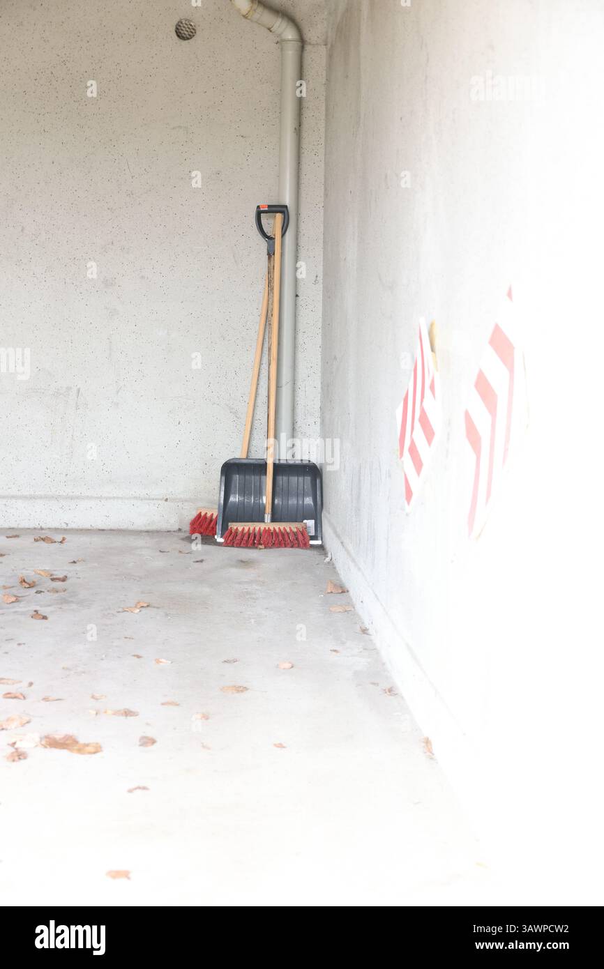 A black and red broom is leaning against a wall Stock Photo - Alamy