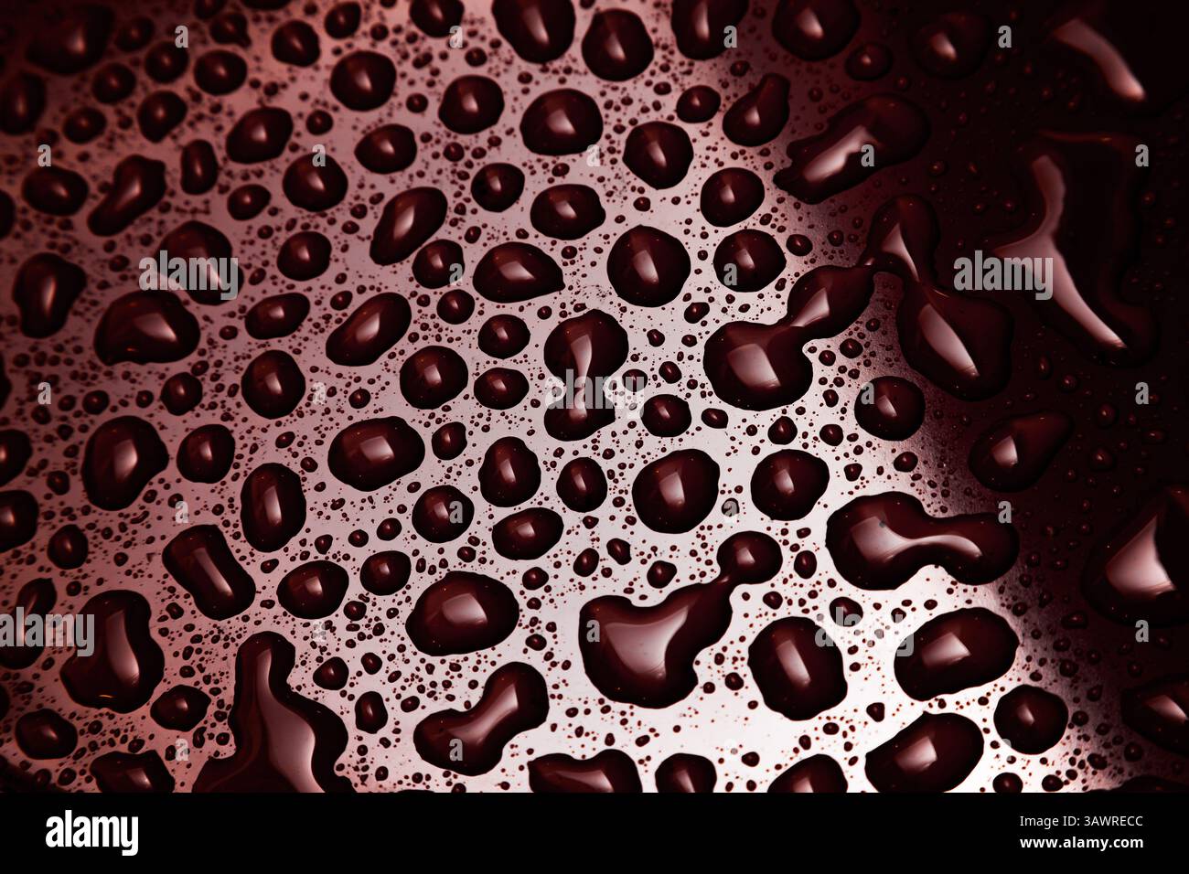Water droplets on a red surface with light and shadow on the surface ...