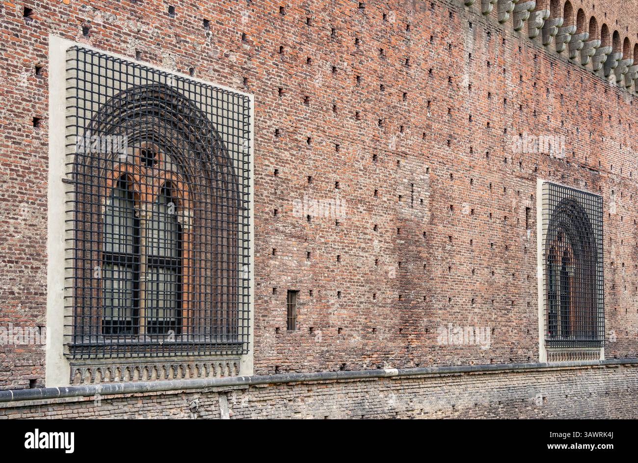 A close-up view of a gothic-style arched window on a medieval brick ...