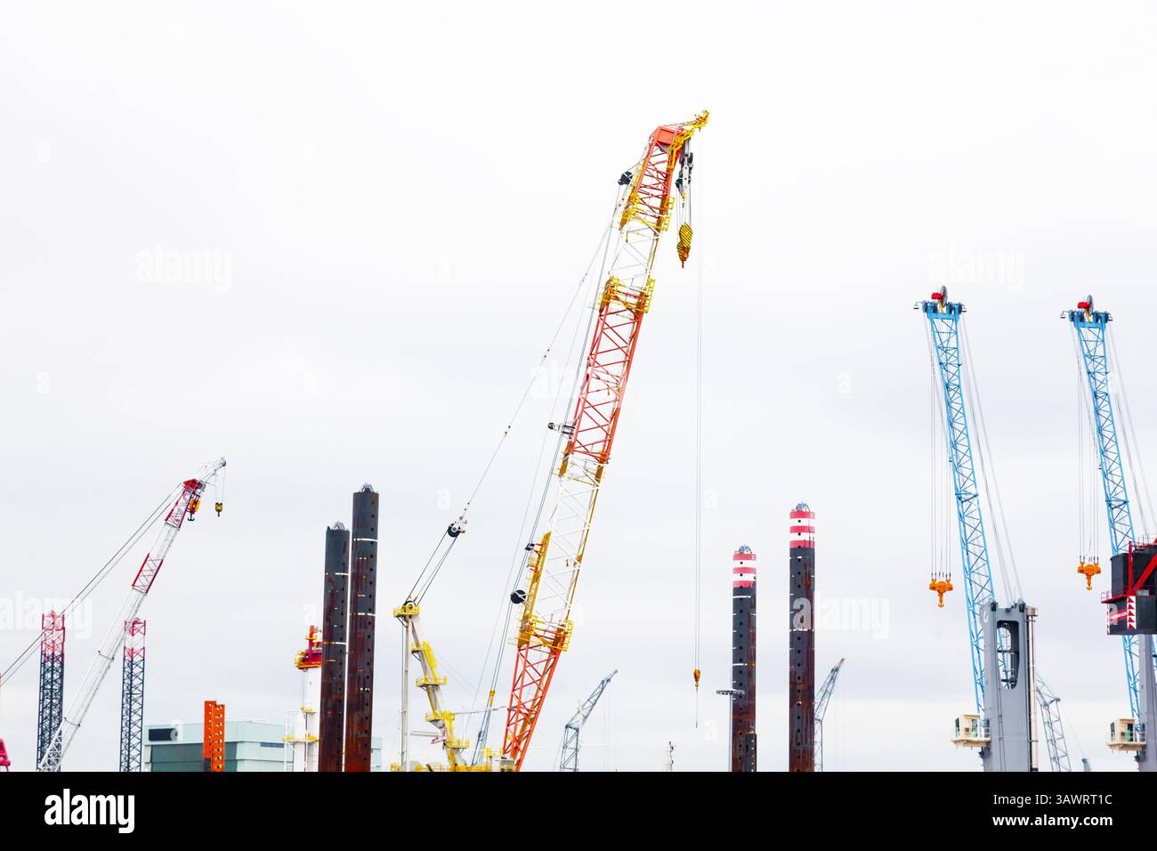 Protruding arrows of port cranes against a cloudy sky Stock Photo - Alamy