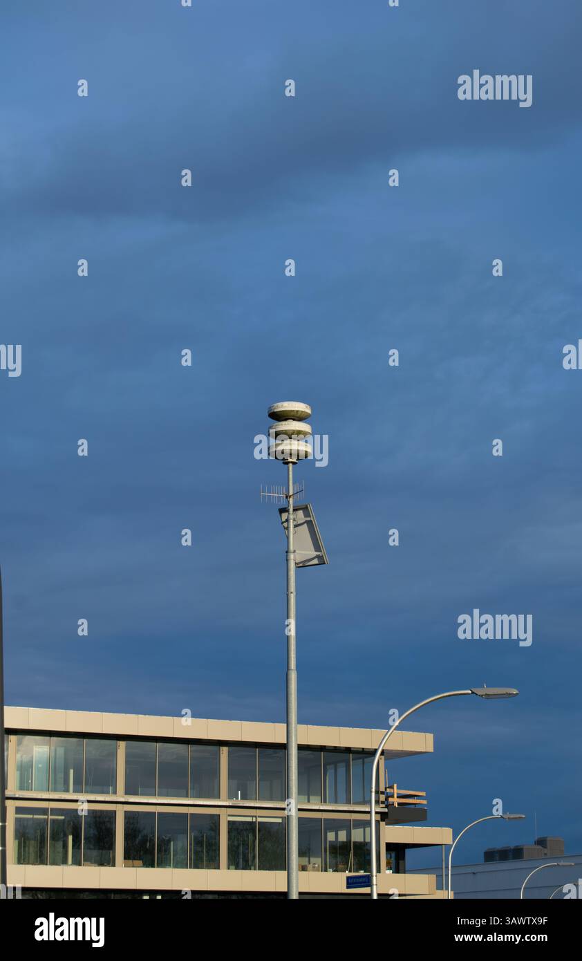 Verticle image of a Dutch air raid siren with antenna on a pole. Blue ...