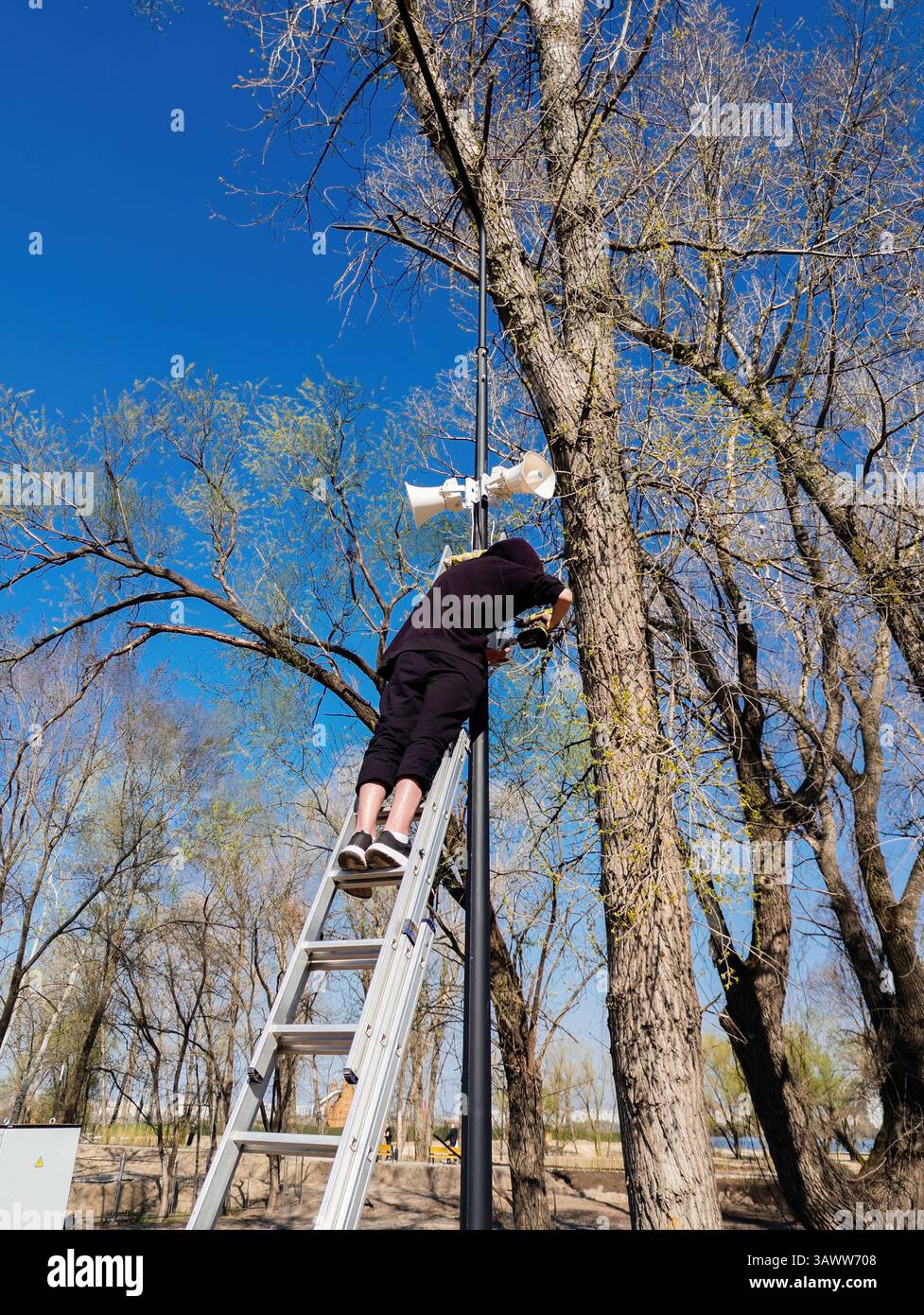 Worker installing security cameras and megaphone on lamp post Stock ...