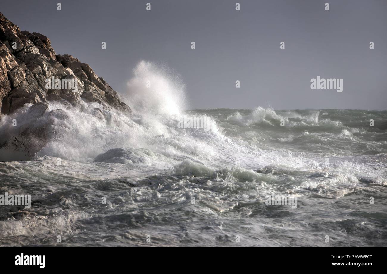 Powerful waves crash against rocky cliffs, capturing the raw energy and ...