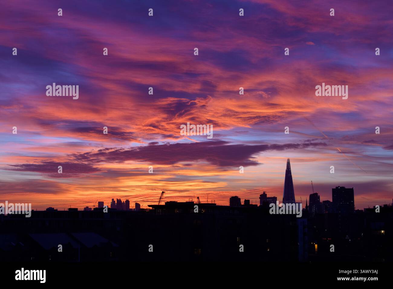 London skyline including the shard in silhouette with dramatic clouds ...