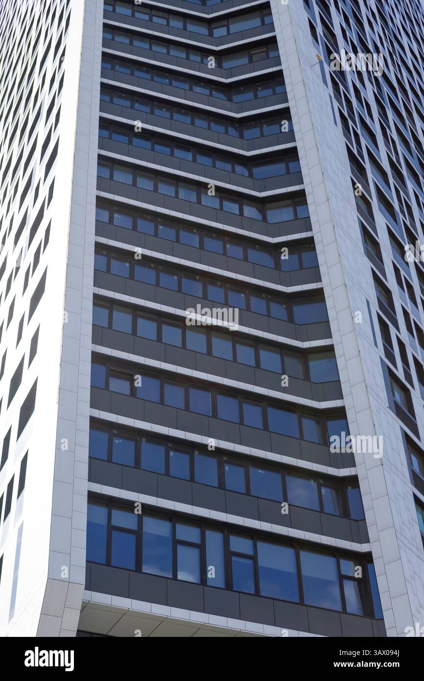 Facade of a tall residential building with sunlit windows reflecting ...