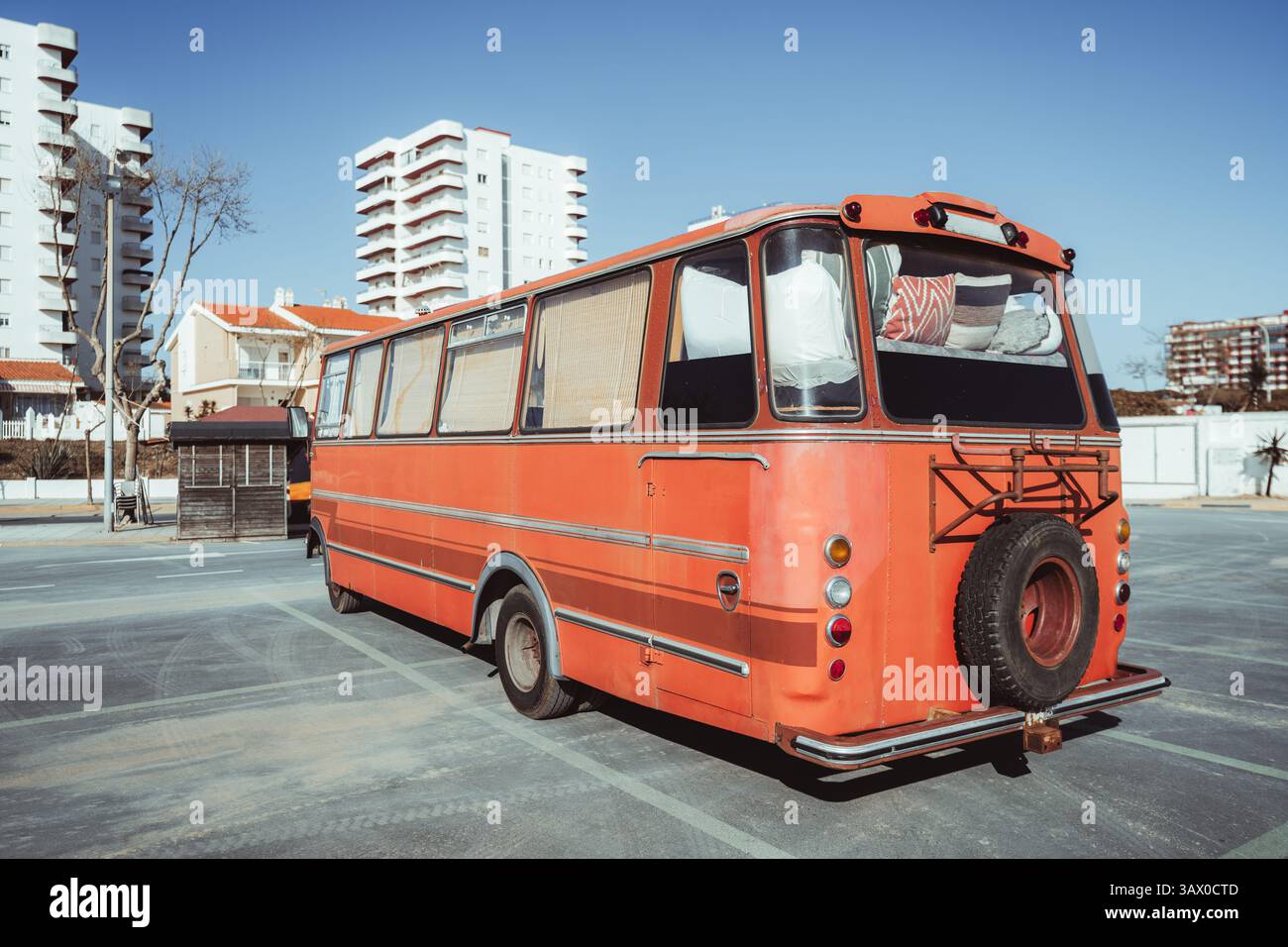 Vintage red bus converted into a camper, parked in urban area with ...