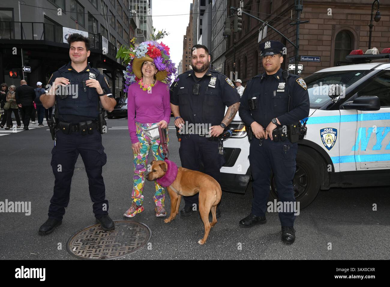 A parade goer wearing a decorative hat and outfit poses with members of ...
