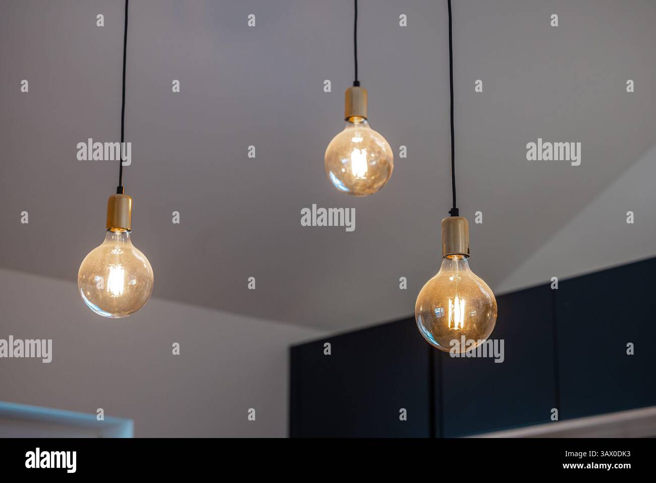 Three exposed Edison bulbs with warm light hang from black cords in a ...