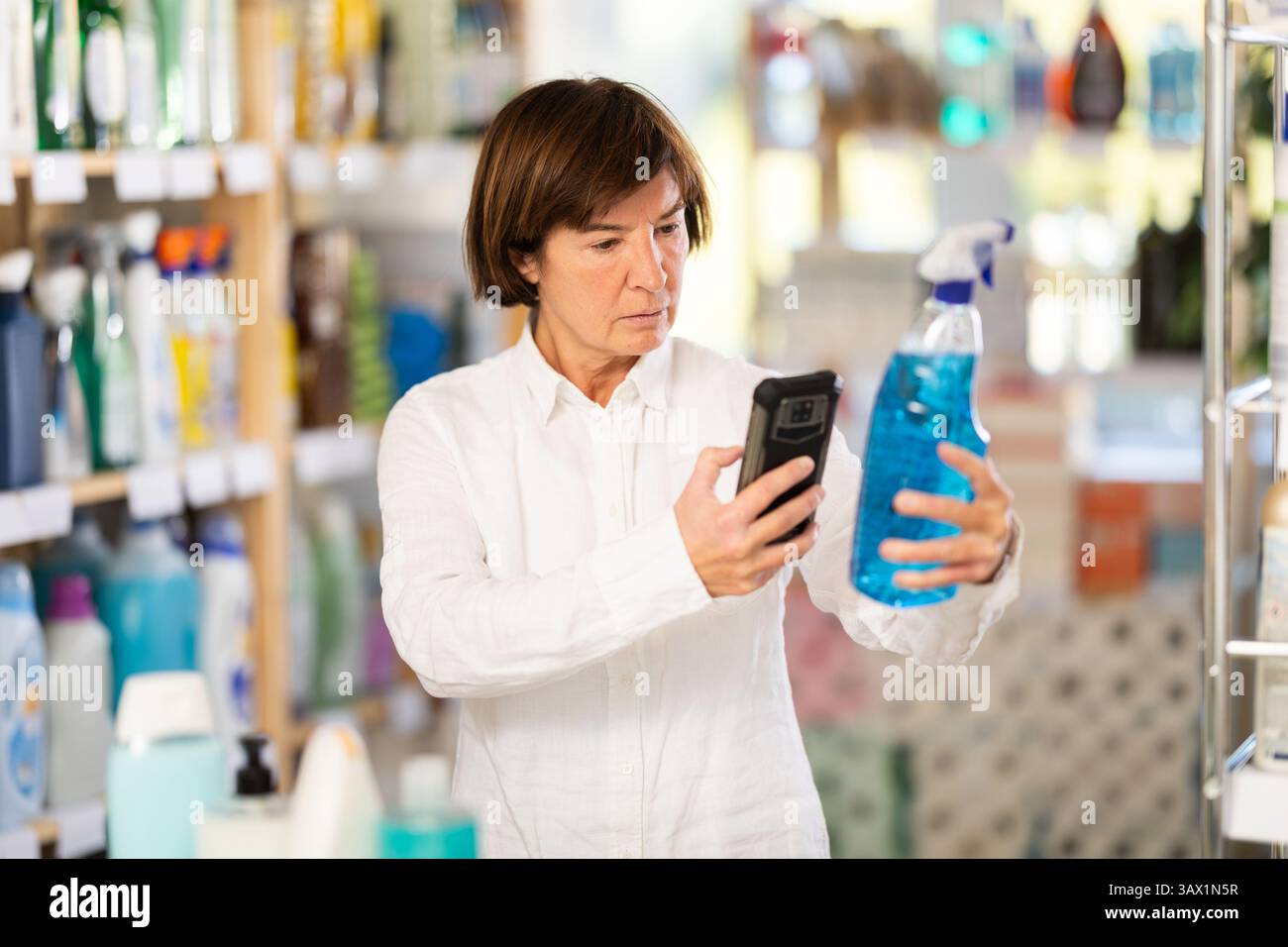 Elderly woman scanning qr code for cleaning spray Stock Photo - Alamy