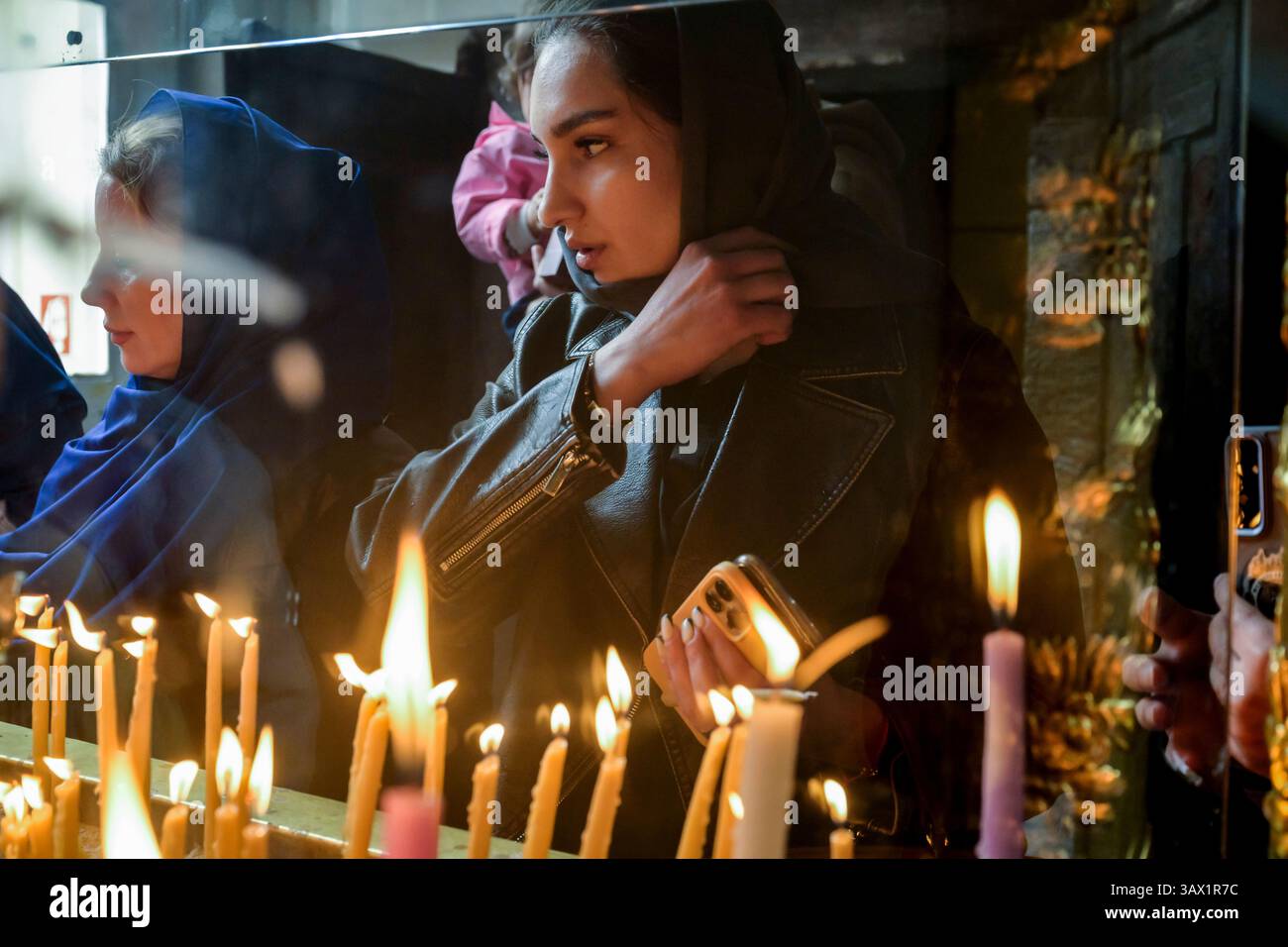 A woman seen before lighting a candle. The Ecumenical Patriarch ...