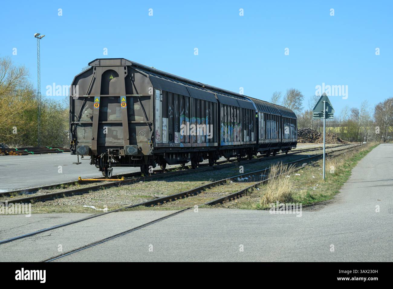An empty train carriage rests on a railway track in a quiet yard ...