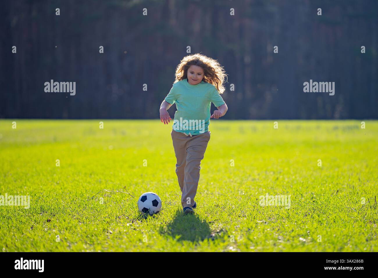 A child play soccer outdoors. A child kicks soccer ball. The kids sport ...