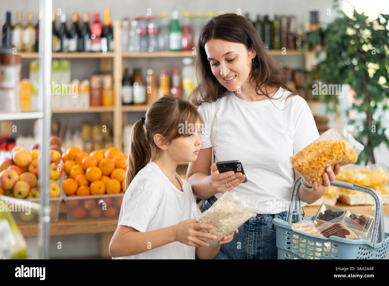 Girl with mother customers at shop scans QR code on cornflakes and oat ...