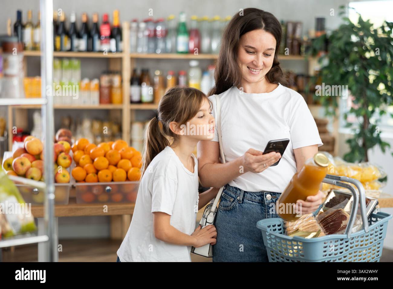 Girl with mother customers at shop scans QR code on juice package using ...