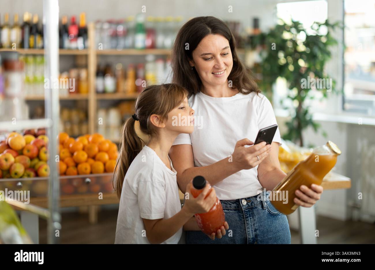 Girl with mother customers at shop scans QR code on juice package using ...