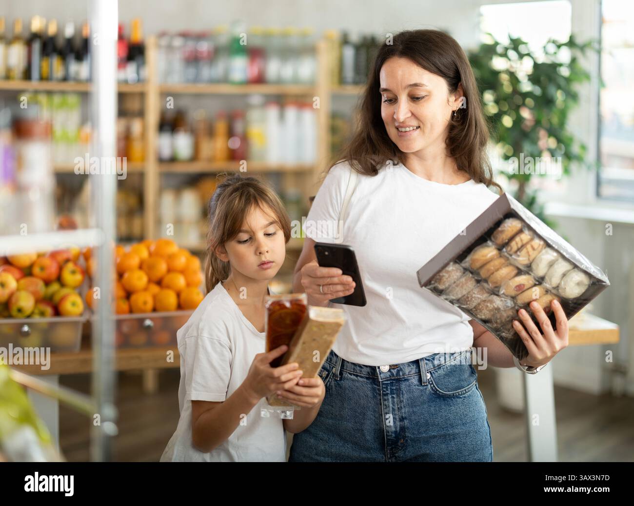 Girl with mother customers at shop scans QR code on sweets package ...