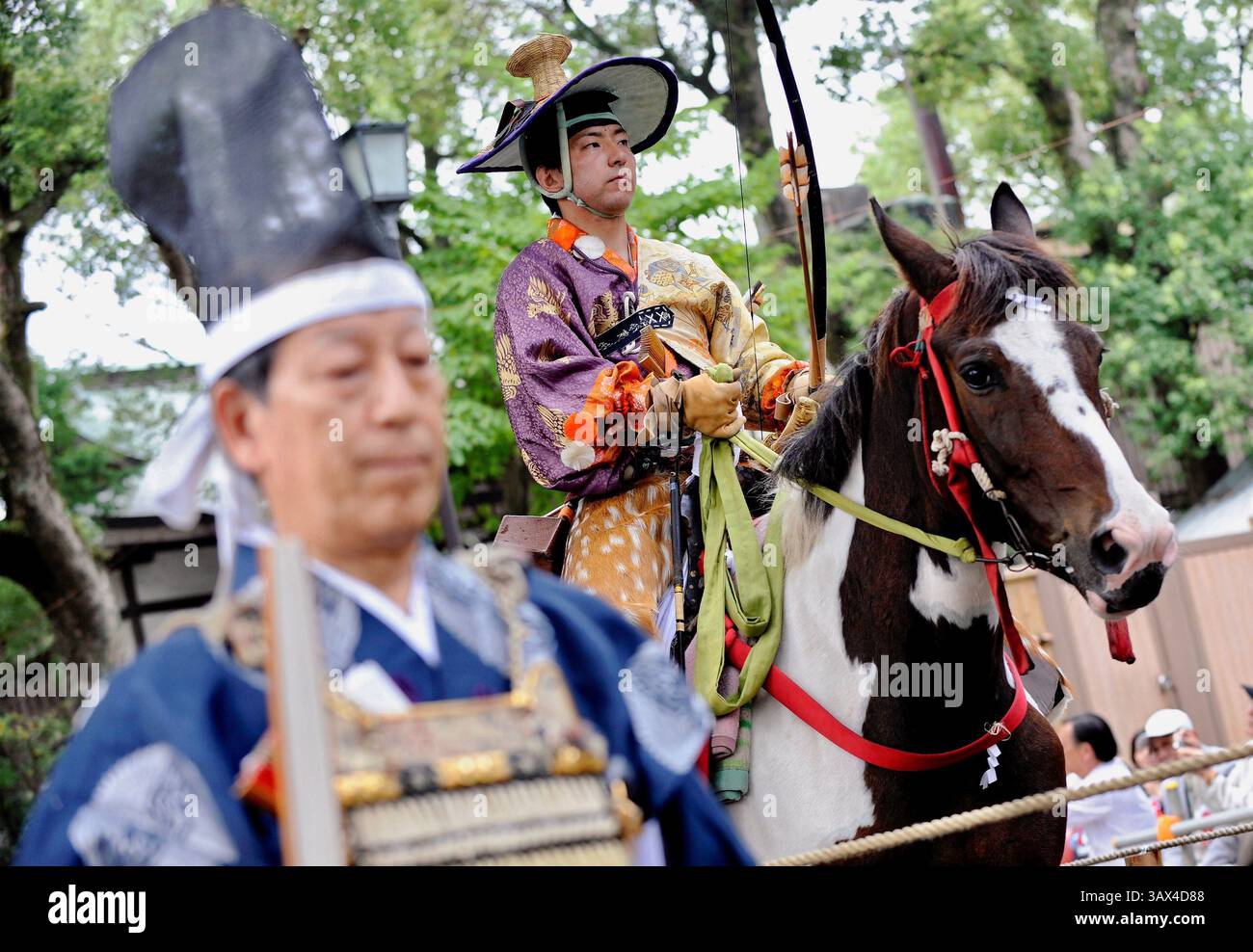 A horseback archer dressed in traditional hunting garb is escorted ...