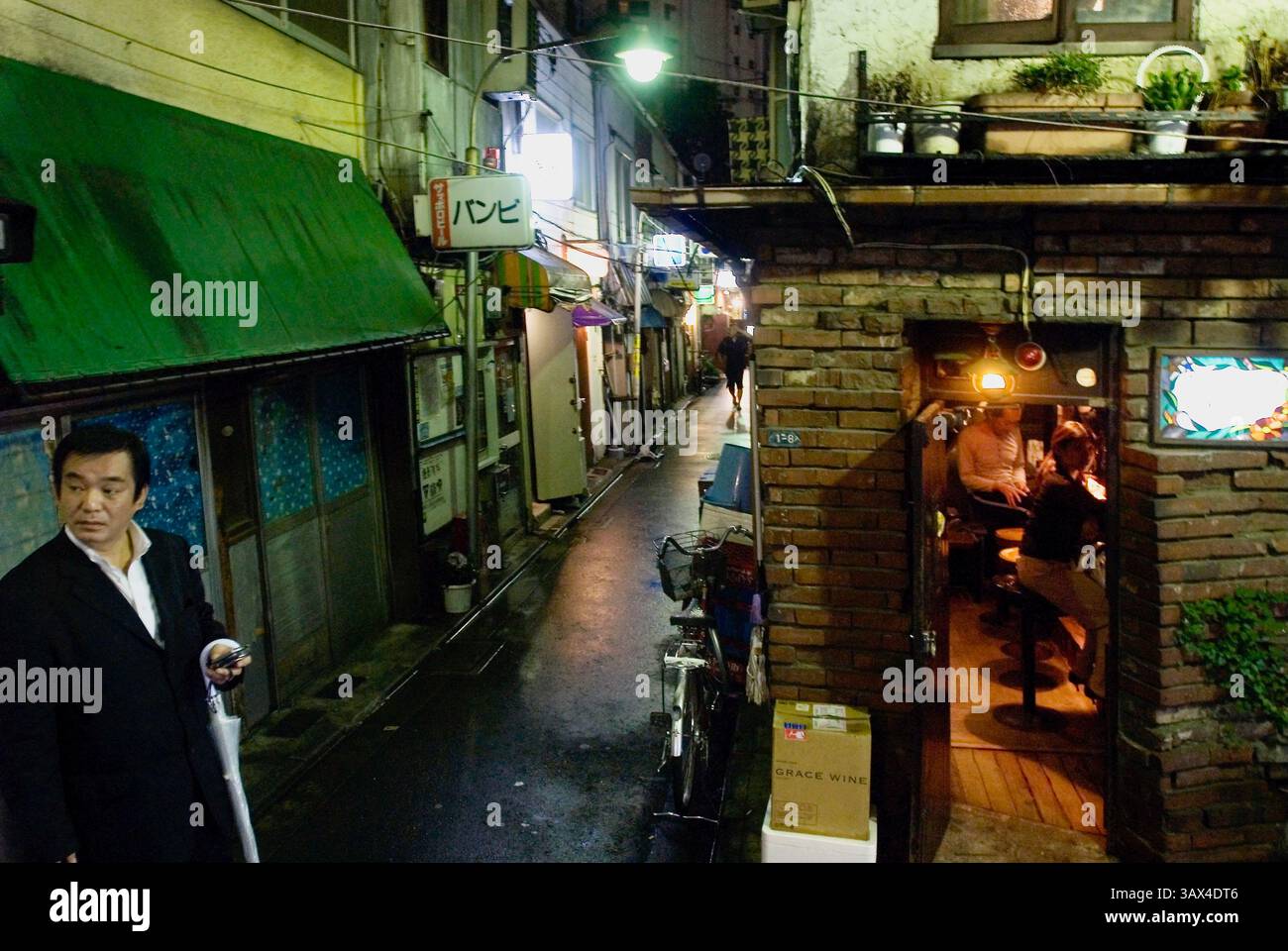 Customers wander past bars in the Golden Gai district of Shinjuku ...