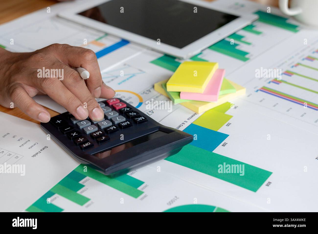 Calculating expenses using a calculator, paper, and financial documents ...