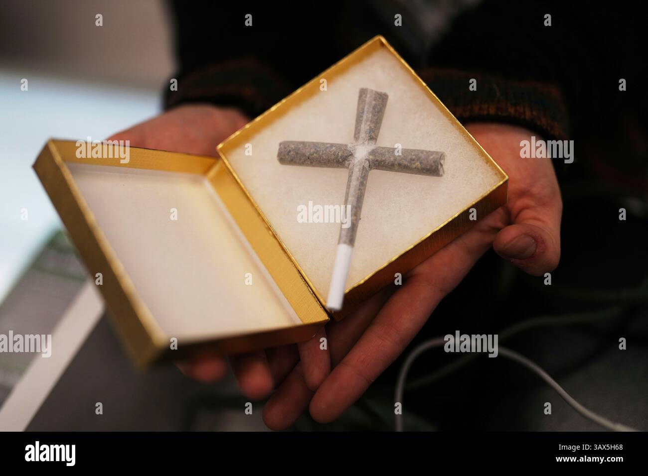 Alexx German displays a joint in the shape of a cross for a customer at ...