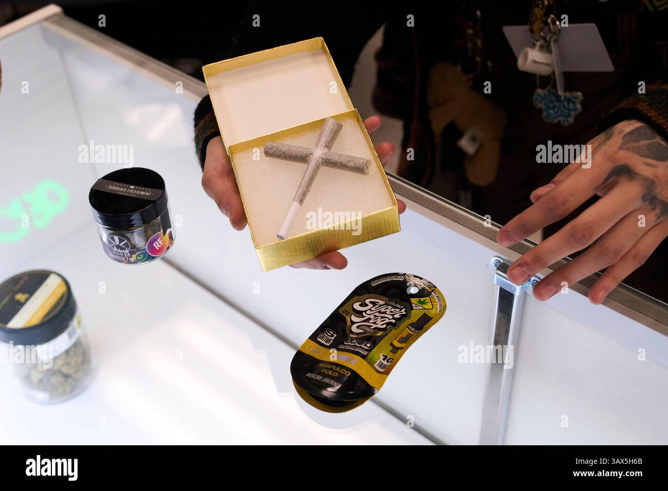 Alexx German displays a joint in the shape of a cross for a customer at ...