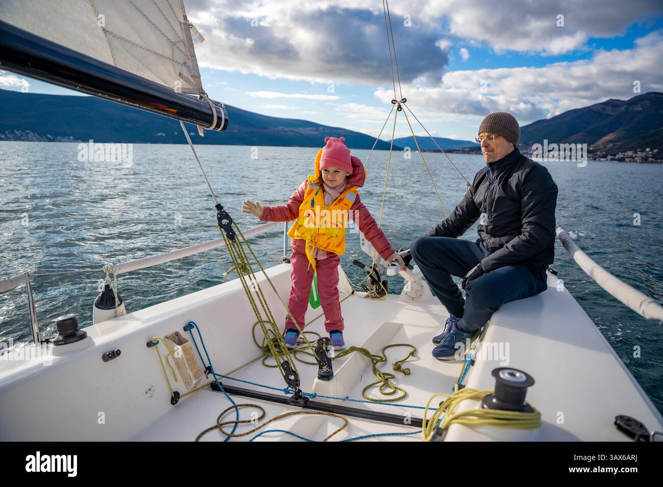 Father instructing daughter on sailing a yacht during training in the ...
