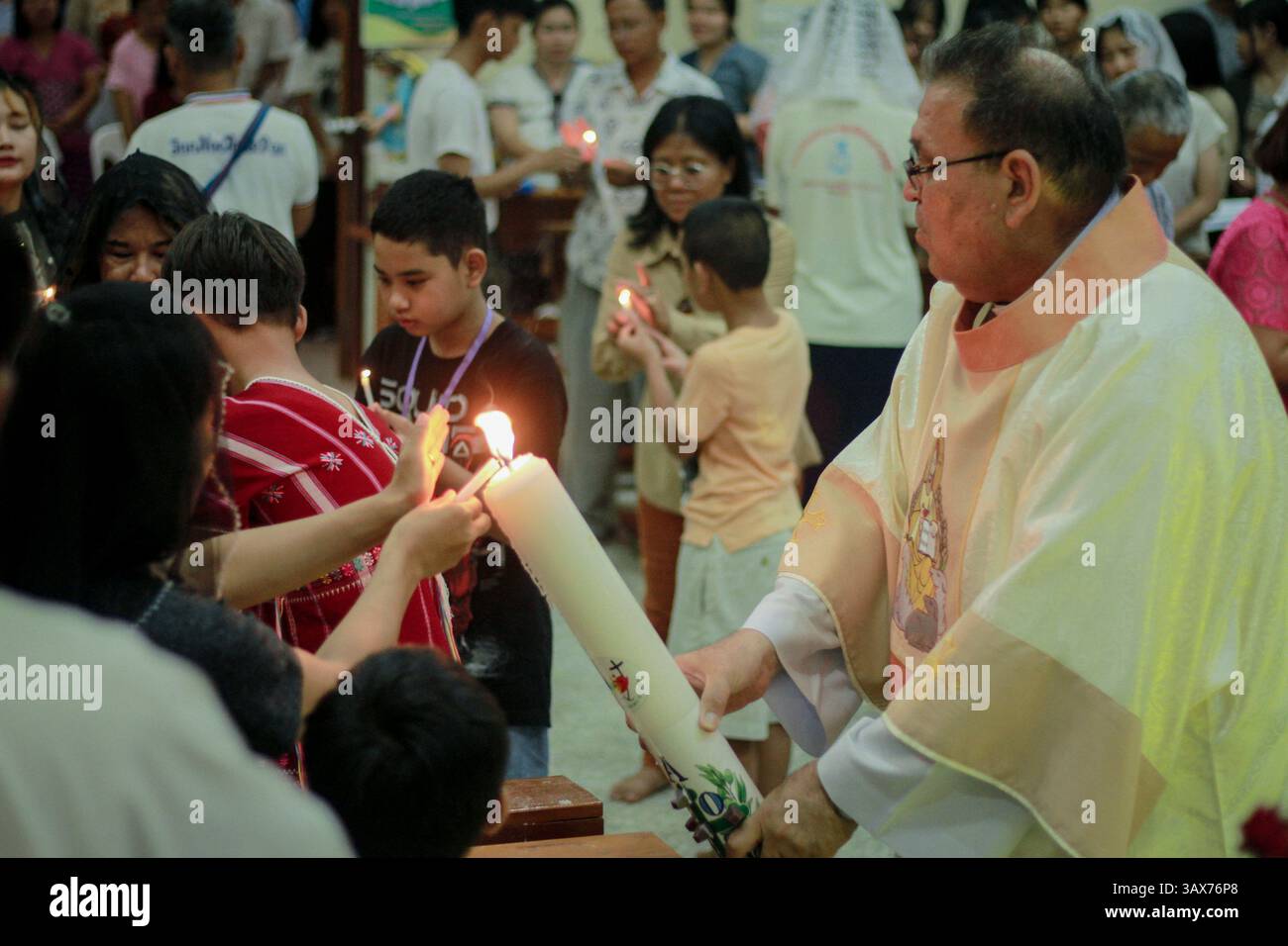 A deacon shares the light from the Paschal candle with the participants ...