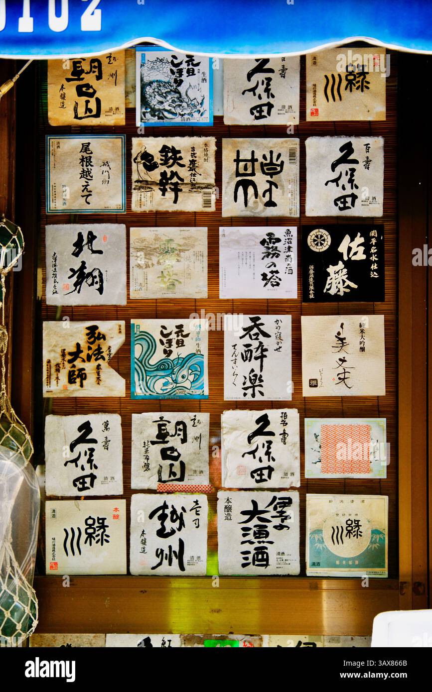 Photo shows sake labels on the exterior of a store in Iyo in Ehime ...