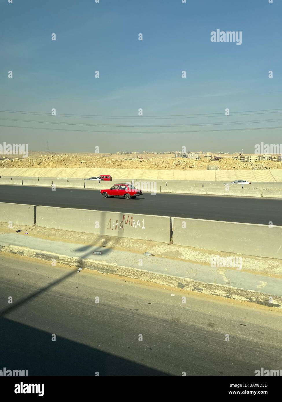 Desert scenery with a red car on the road trip from Hurghada to Cairo ...