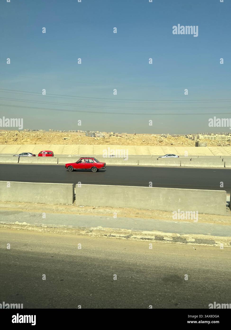 Desert scenery with a red car on the road trip from Hurghada to Cairo ...