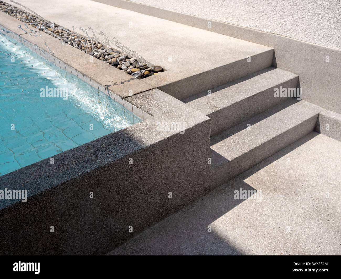 Exposed aggregate finish pool decks with steps with splashing water ...