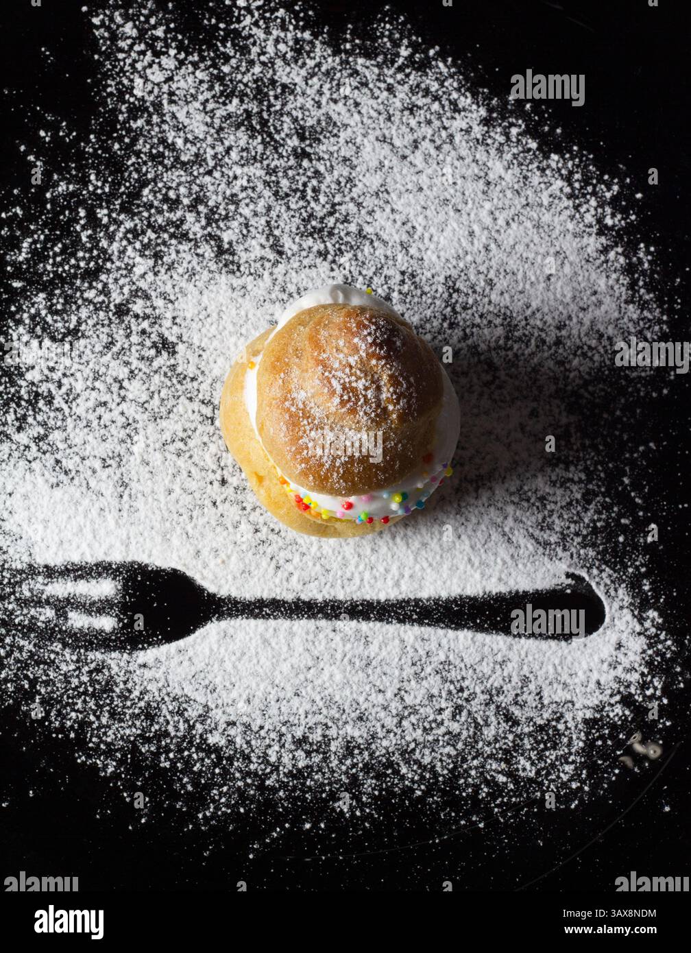 Cream puffs on a black plate sprinkled with icing sugar Stock Photo - Alamy