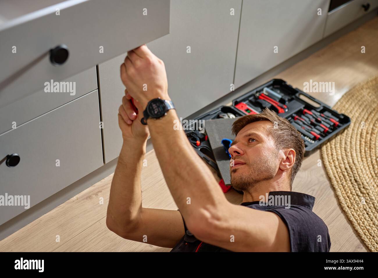 Man assembling kitchen drawer in modern cabinet using screwdriver ...