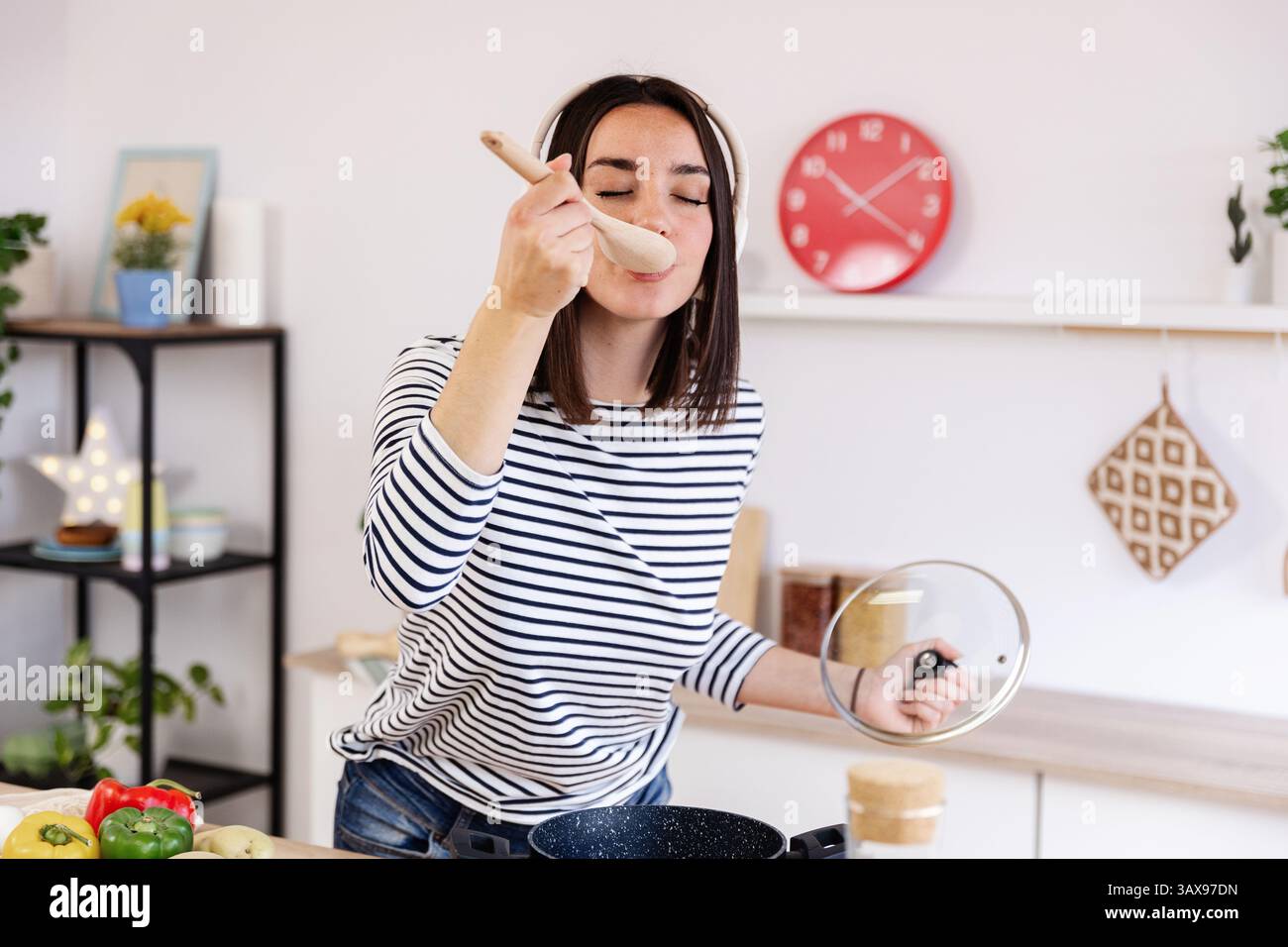 Young woman tasting food while cooking in modern kitchen at home Stock ...