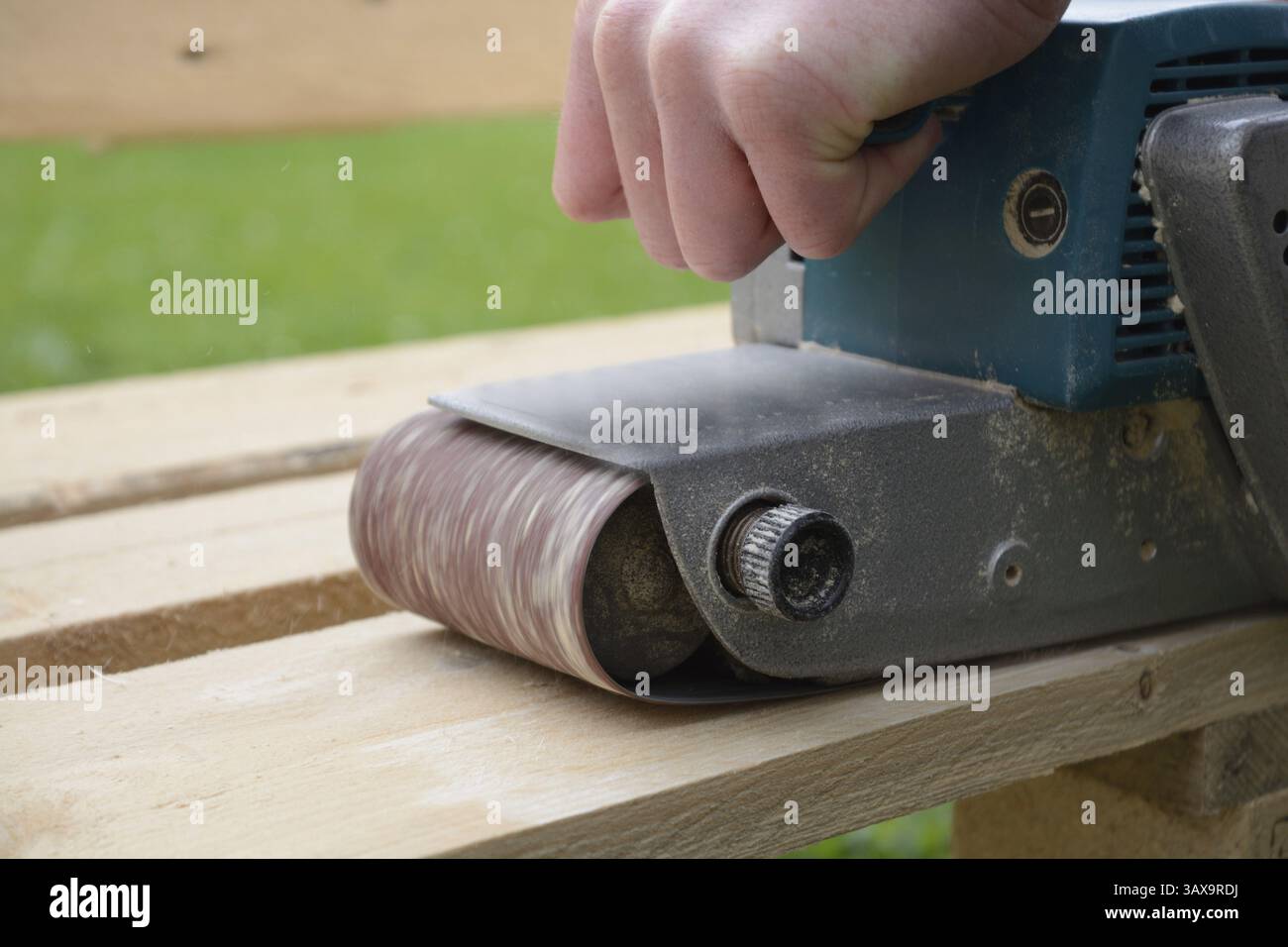 Person sanding softwood with a hand belt sander Stock Photo - Alamy