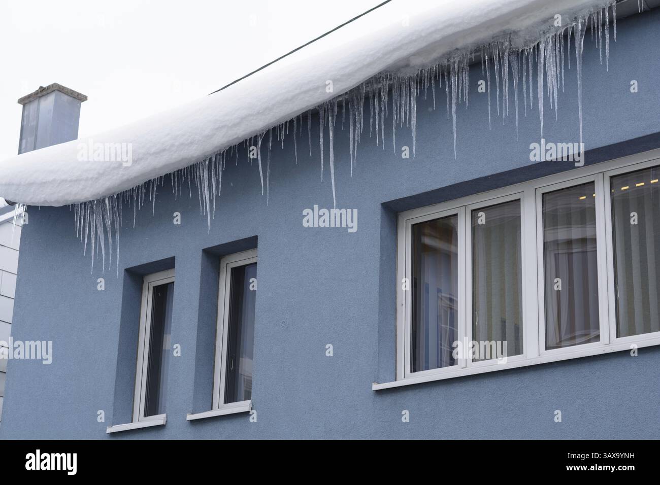 Large icicles and snow hanging from the roof - close-up Stock Photo - Alamy