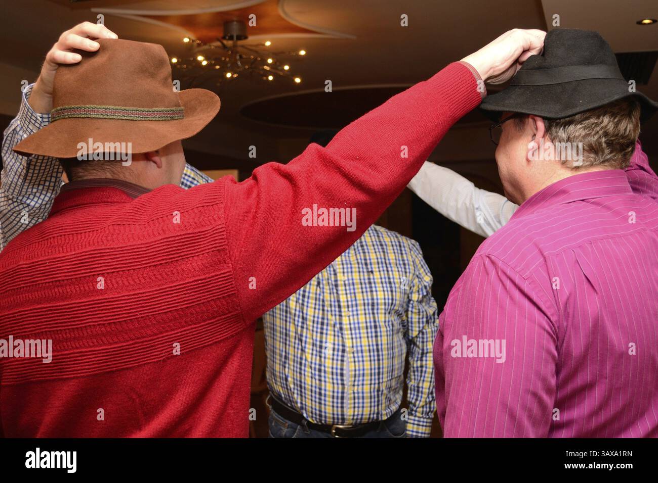 Men swap hats in a game at a birthday party Stock Photo - Alamy