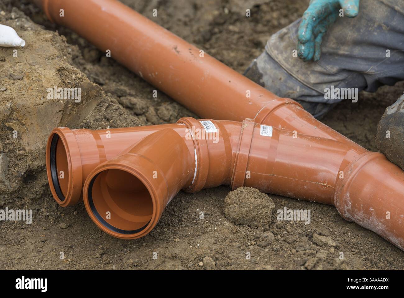 Construction worker lays PVC sewer pipes on construction site - branch ...
