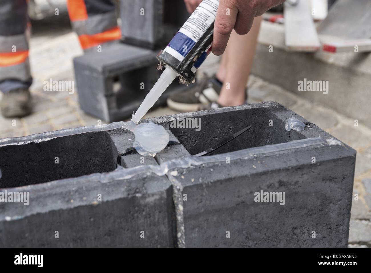 Bricklayers working in the building trade with a tube of silicone and ...